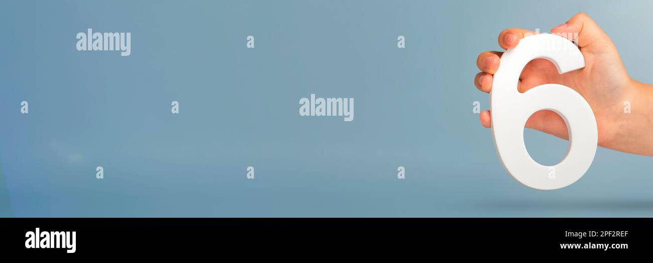 Number six in hand. A hand holds a white number 6 on a blue background ...