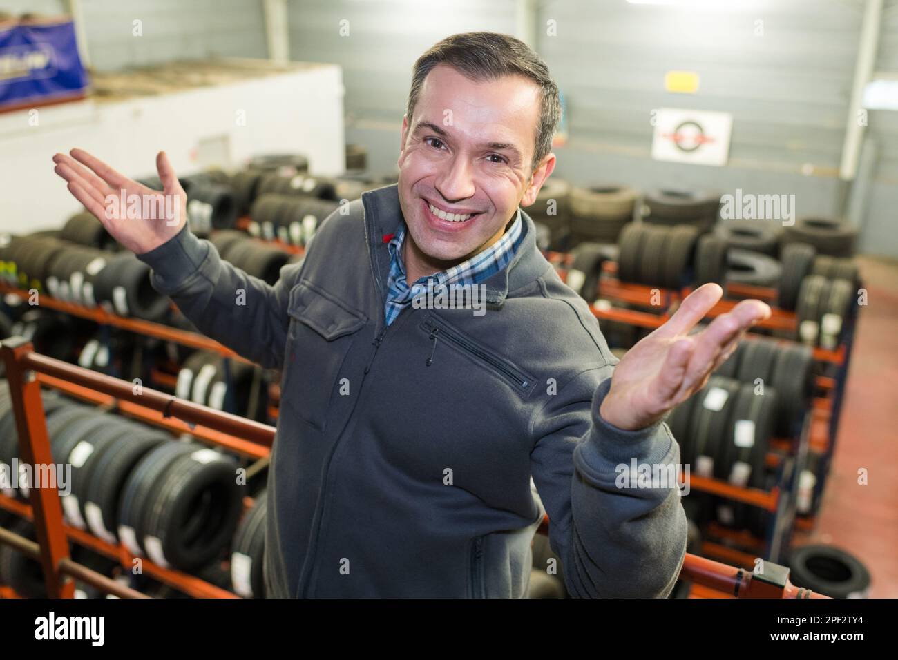 technician man promoting new tyres in car tire shop Stock Photo - Alamy