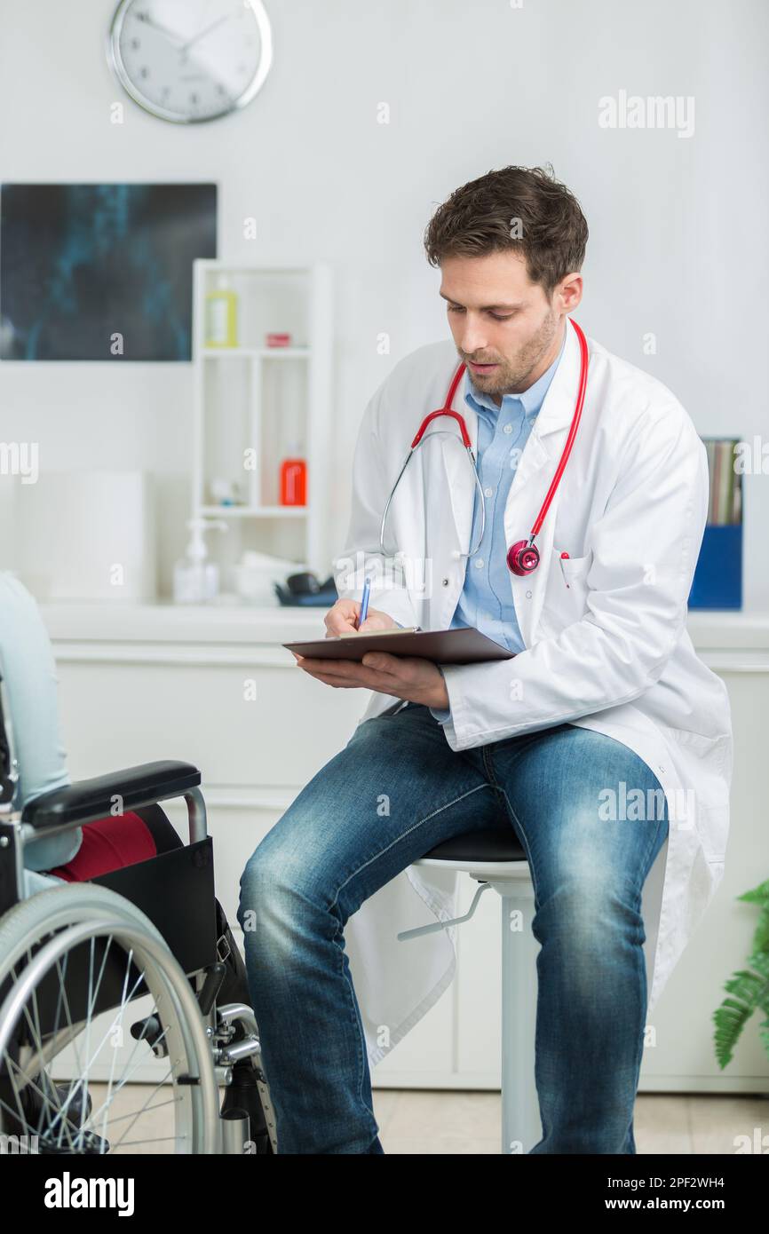 doctor writing prescription to disabled patient Stock Photo - Alamy