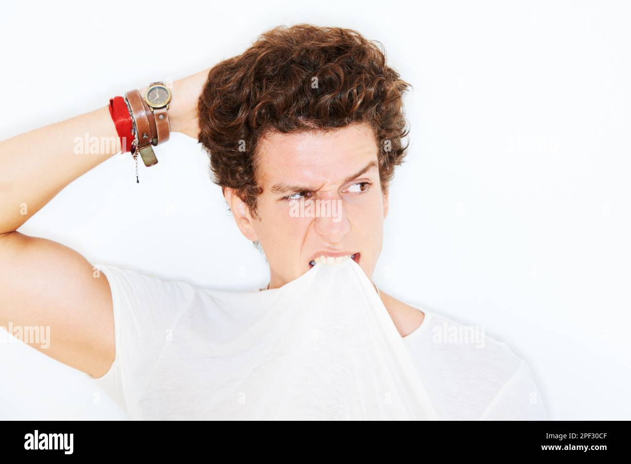 Hes got plenty of attitude. Studio shot of a young man biting the neck ...