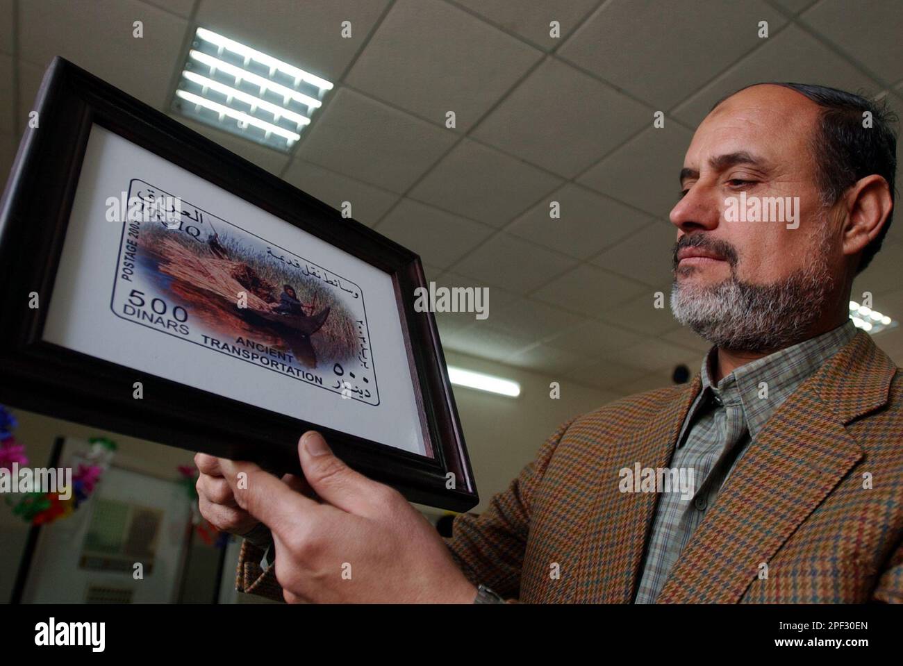 Post office employee Abed Alhussein Farhan shows a framed reproducion ...