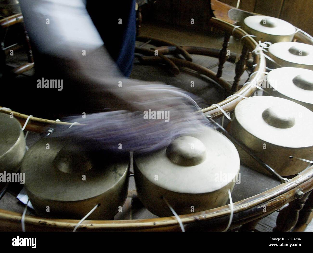 Chea Chanthou, 15-year-old Cambodian student, wipes the dust from traditional circular gongs ...