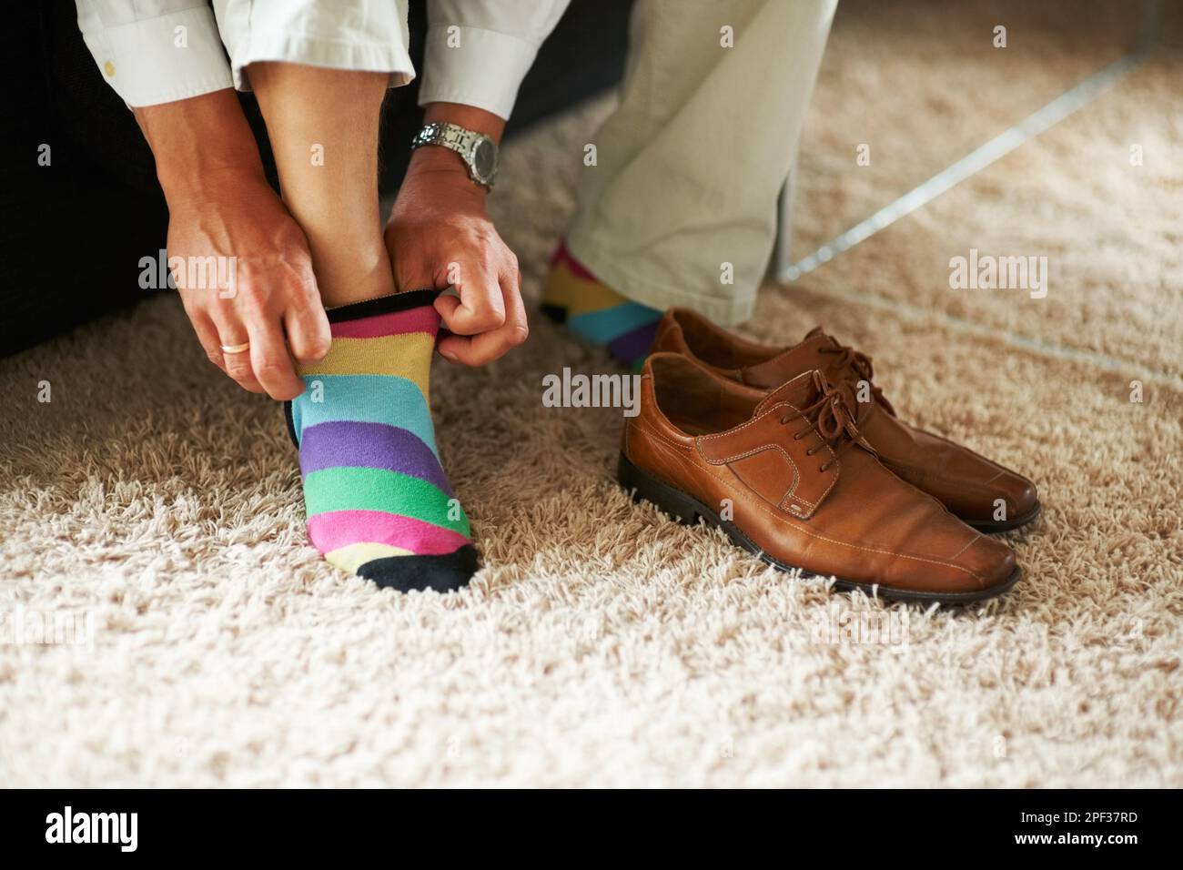 Adding a little bit of fun to the outfit. a man putting on colourful ...