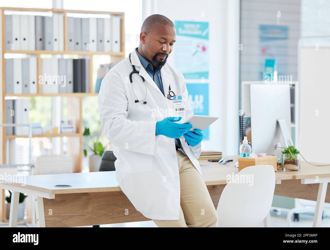 Mature doctor using his digital tablet in the hospital. African ...