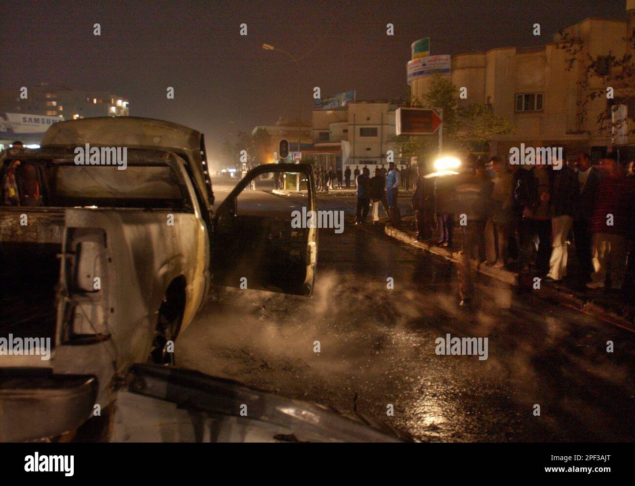 Iraqis look at a pickup truck which exploded in central Baghdad Sunday ...