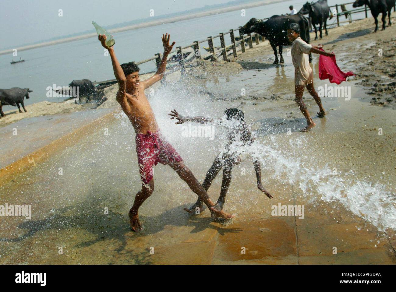 Indian boys play in the spray of a firehose used by workers to clear ...