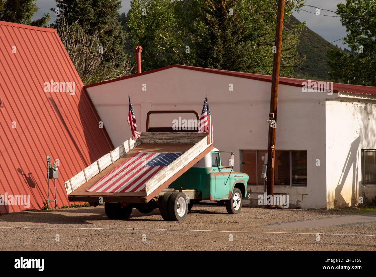 A flat bed truck decorated with three American flag, a large flag lying ...