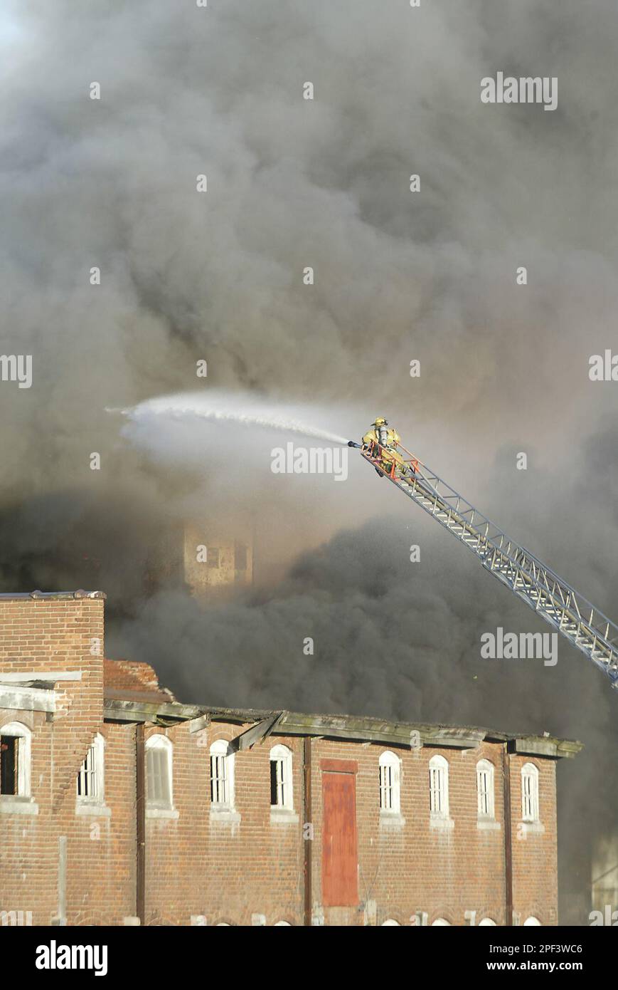 A firefighter douses the Greenhalgh mill complex in Pawtucket, R.I., as ...