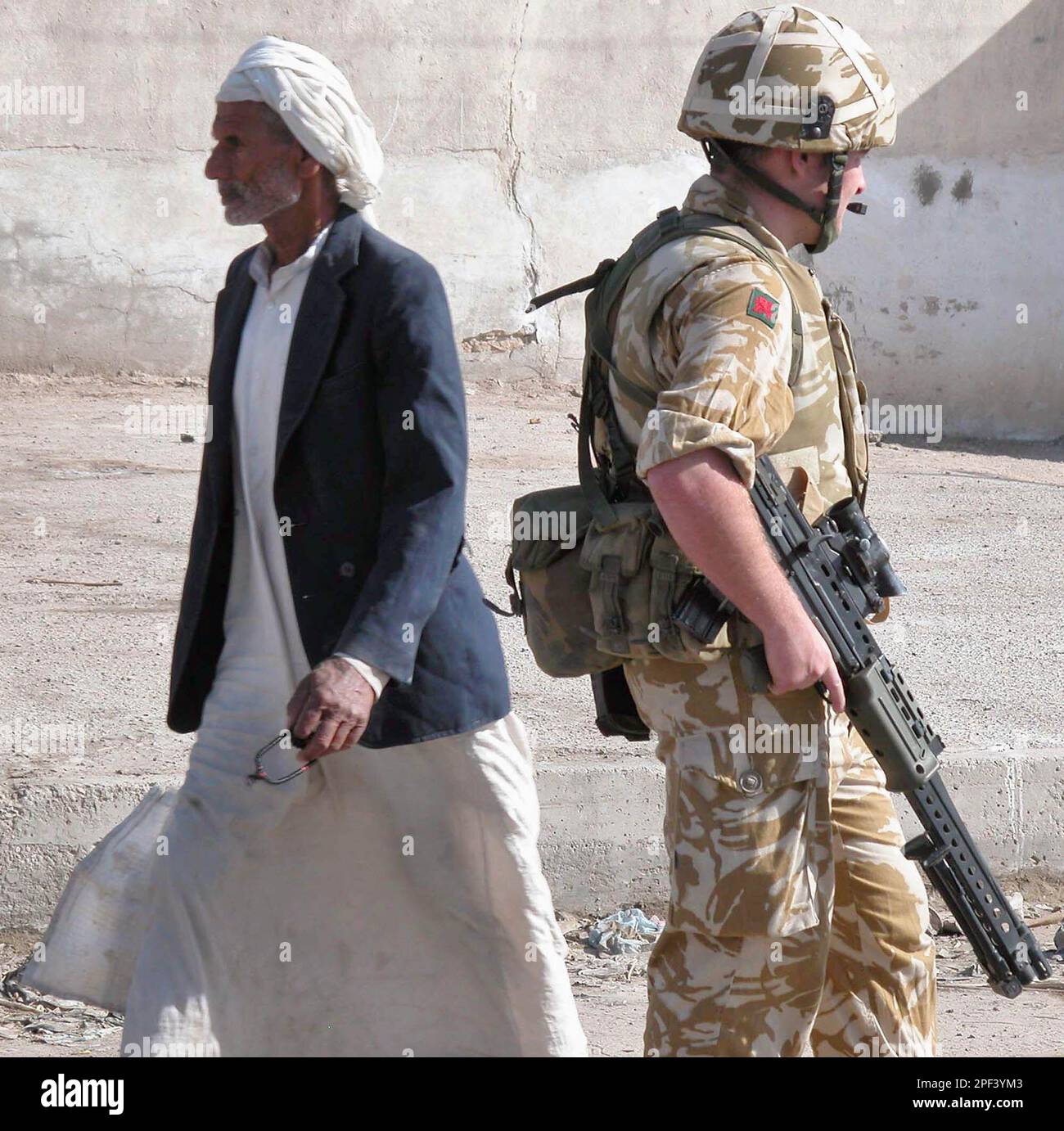 A British Army soldiers pass an Iraqi man in the center of Basra ...