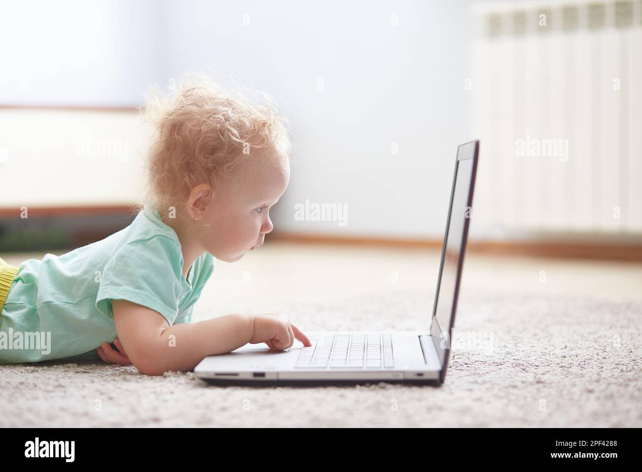 small child at a computer lying on a carpet in a living room Stock ...