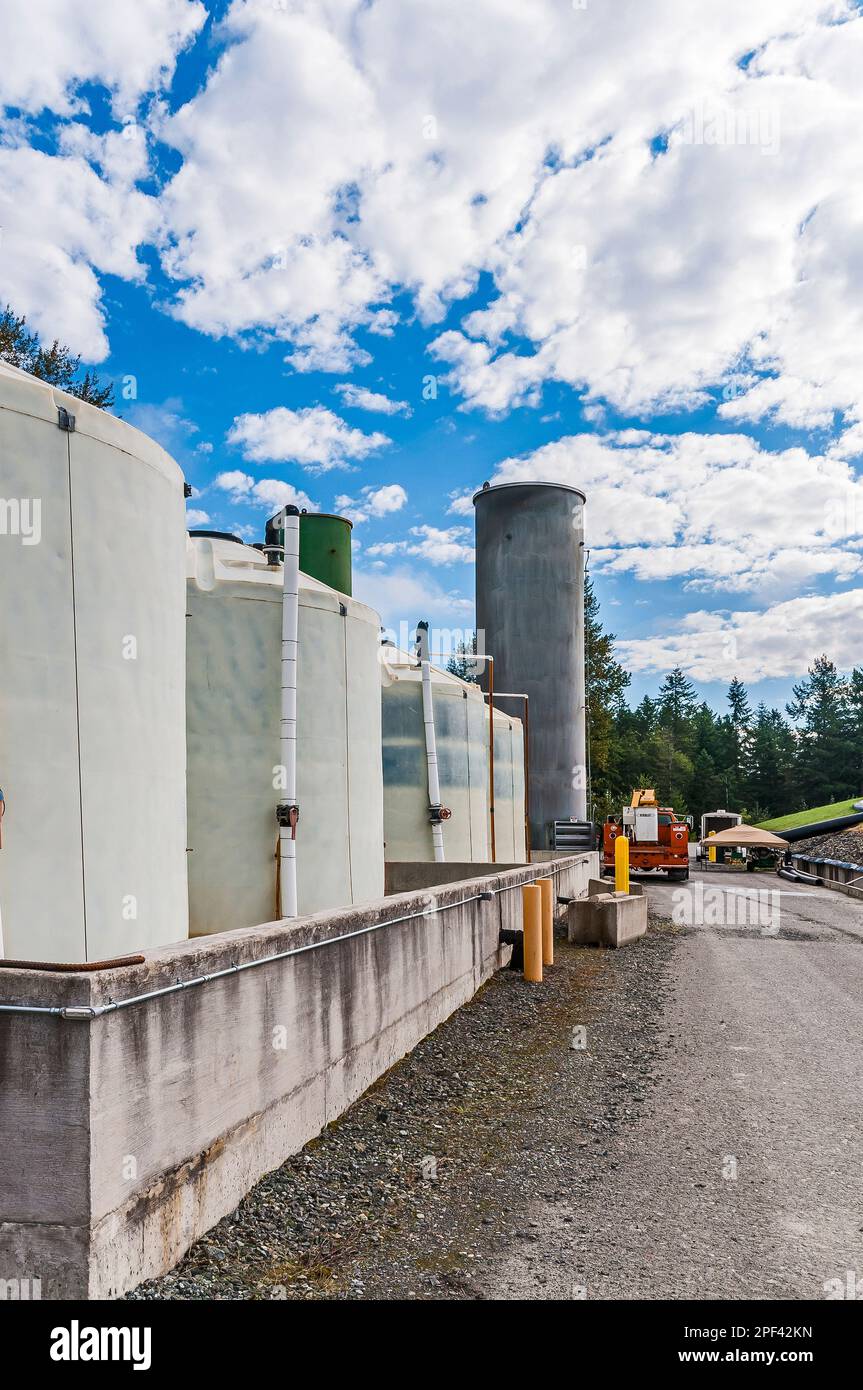 A row of storage tanks and containers behind a concrete wall in an ...