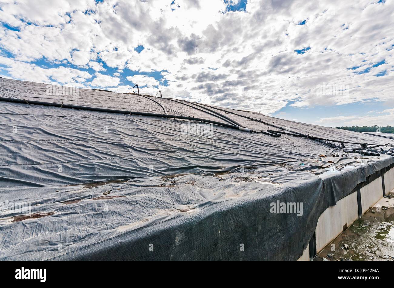 A concrete box culvert in the foreground with a geomembrane covering ...