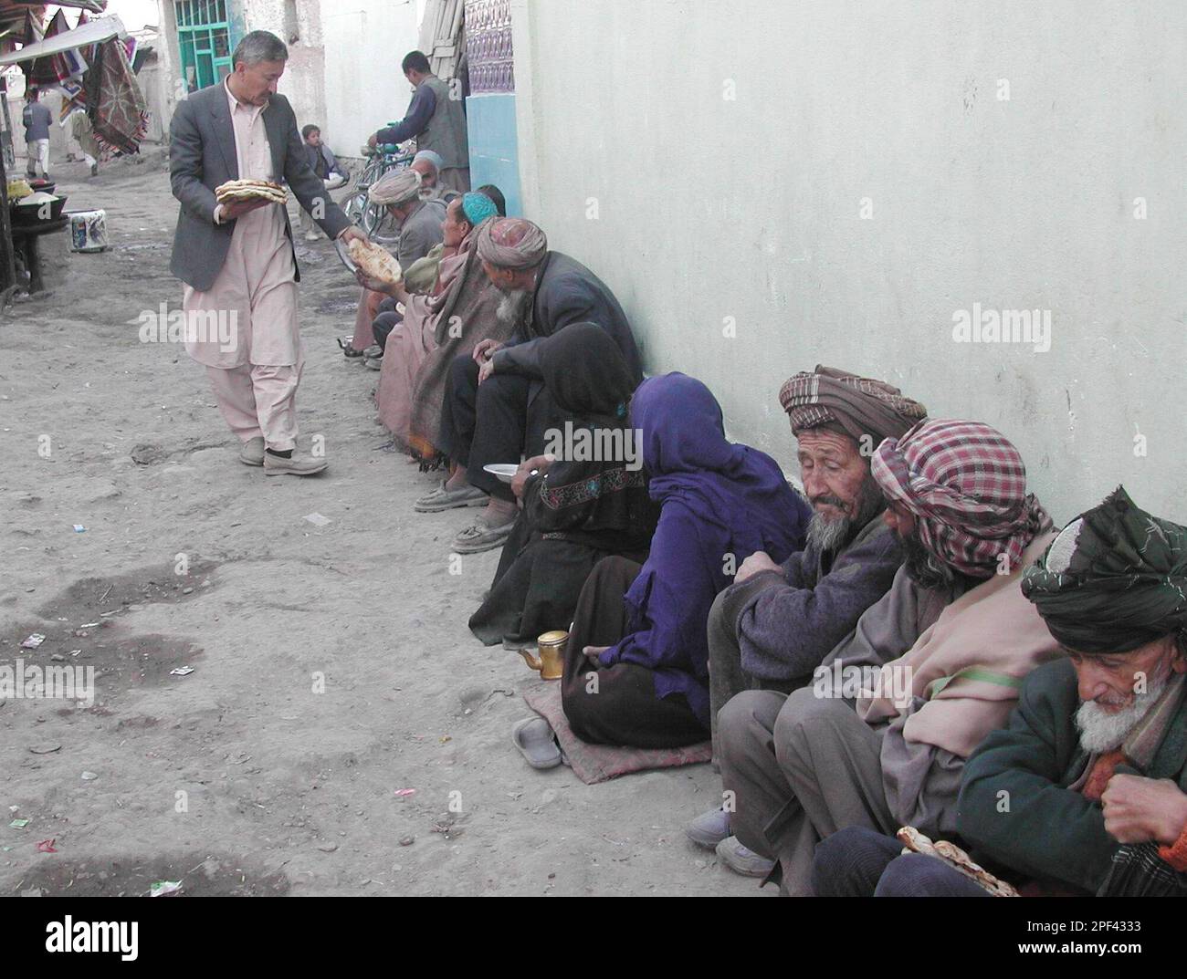 An Afghan man offers bread to the poor people in the front of a Shiite ...