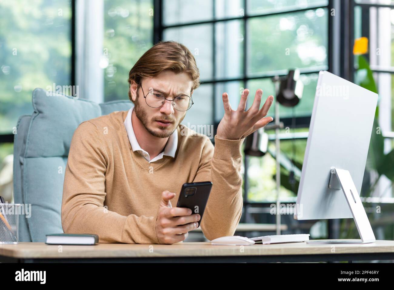 An angry and shocked man sits in the office at the table and looks ...