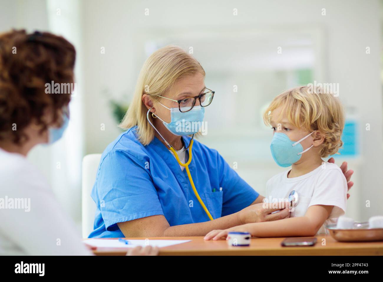 Pediatrician doctor examining sick child in face mask. Ill boy in ...