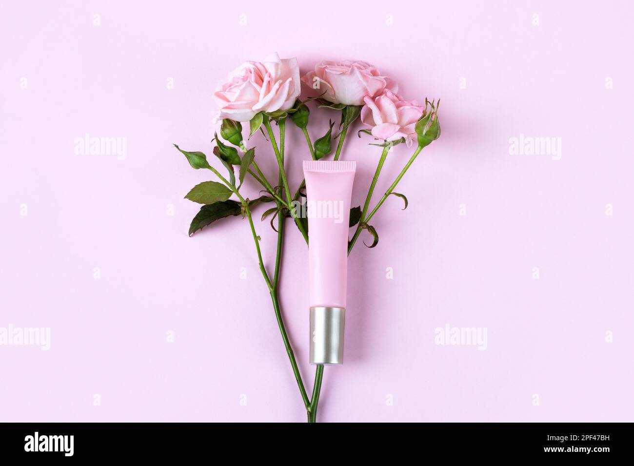 Cosmetic bottle container on a pink background with a roses. Top view ...