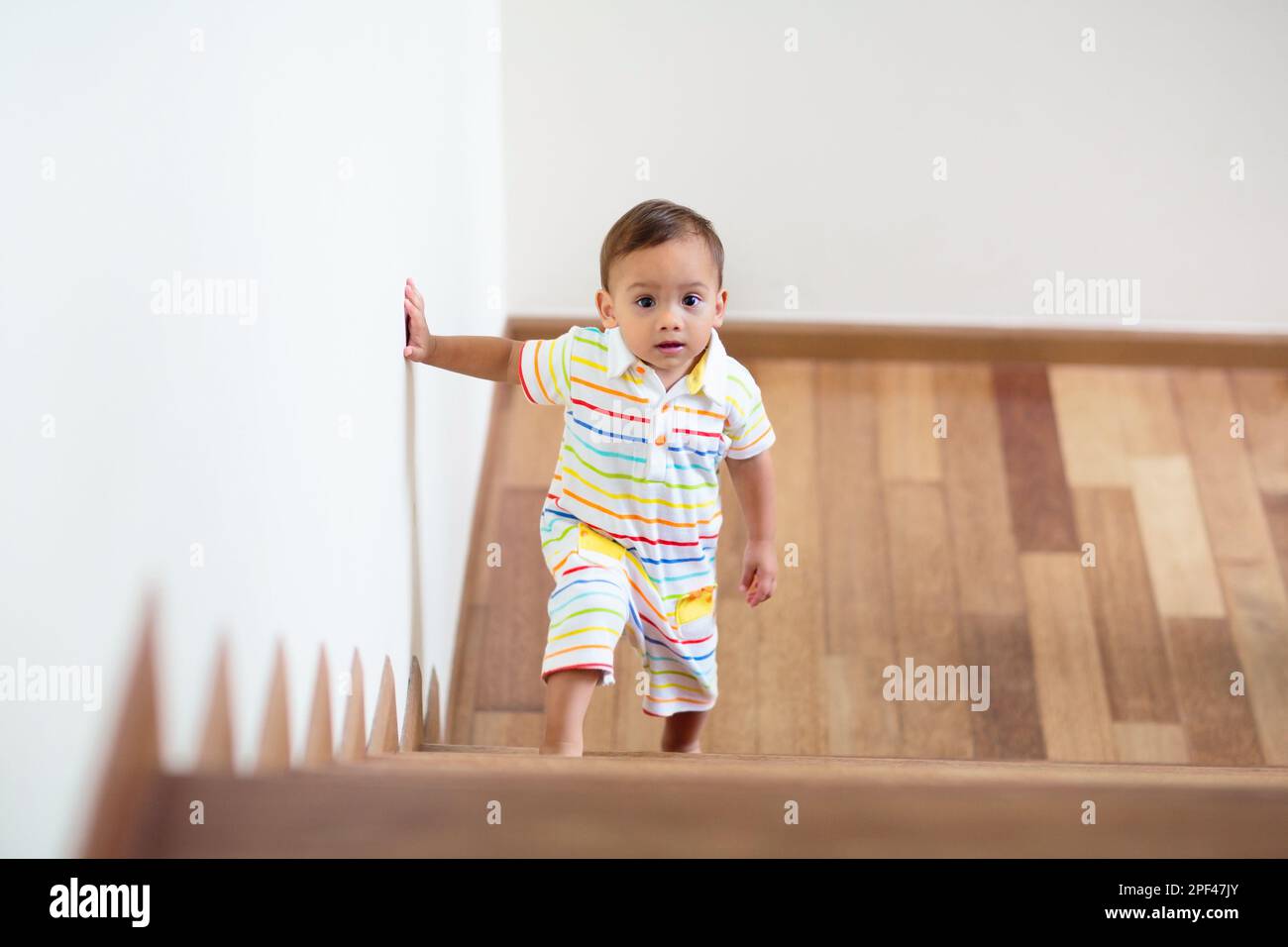 Kid walking stairs in white house. Asian baby boy playing in sunny ...
