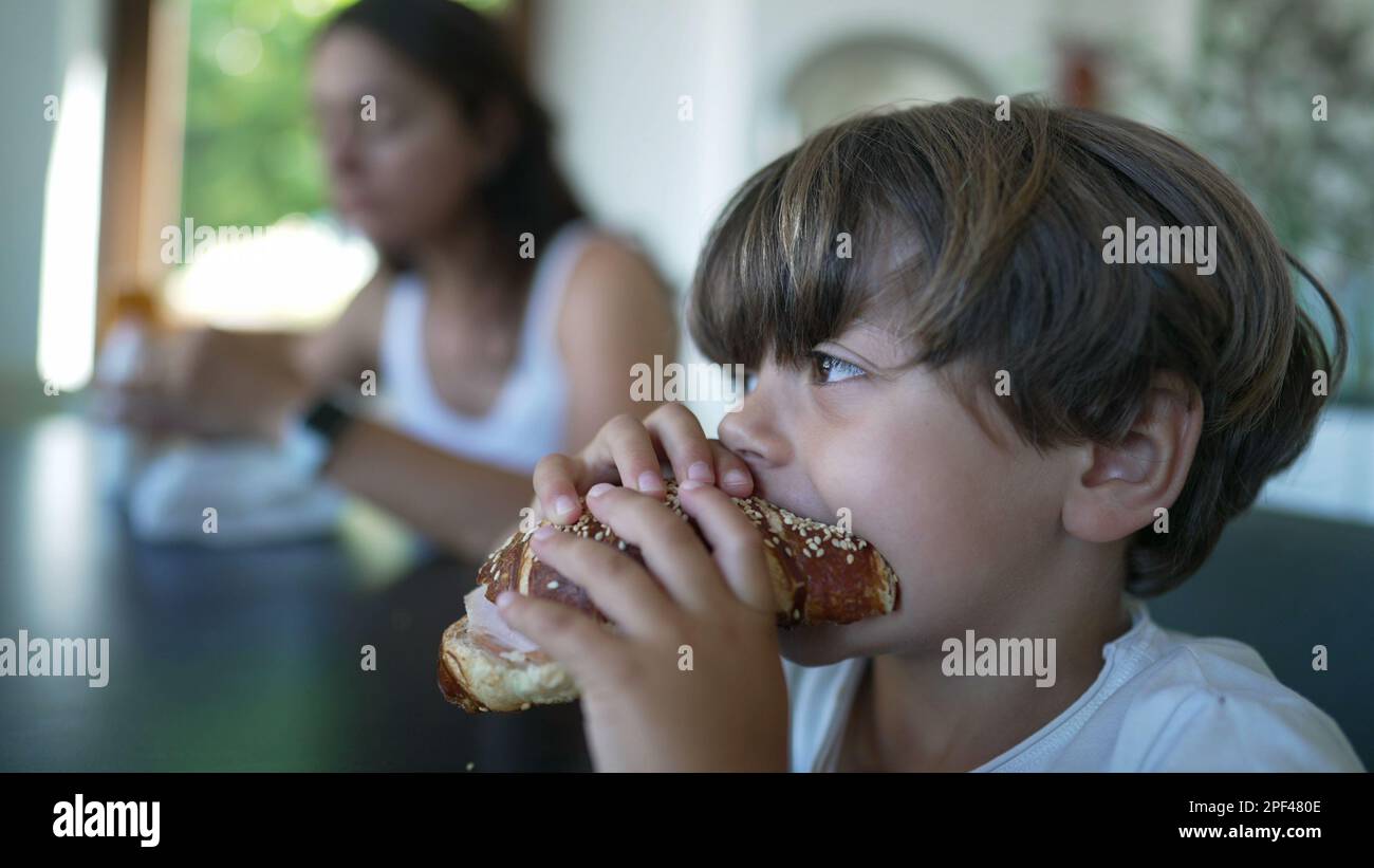 Little boy eating sandwich. Child taking a bite of bread. Kid eats ...