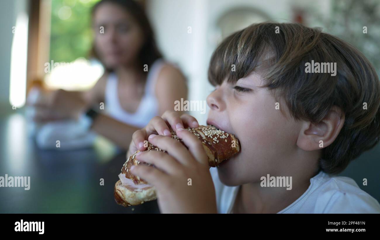 Little boy eating sandwich. Child taking a bite of bread. Kid eats ...