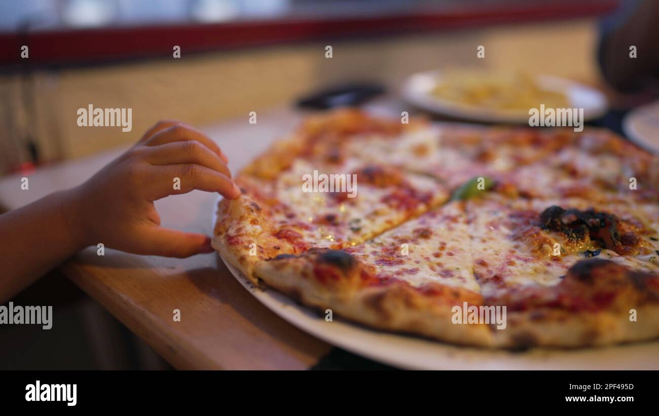 One hand grabbing piece of pizza on plate. Child hands taking a slice ...