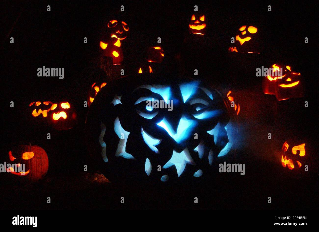 A giant jack-o-lantern glows blue as smaller jack-o-lantern surround ...