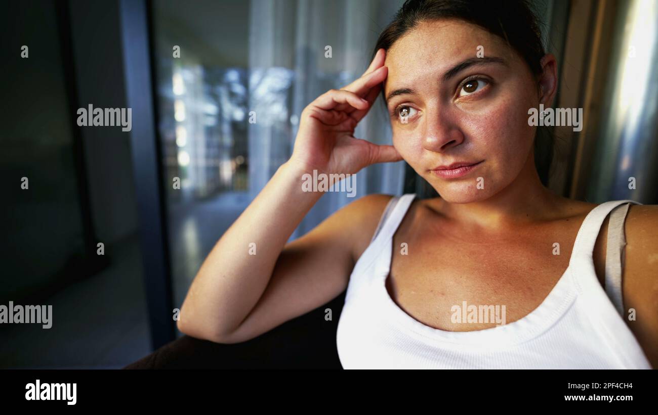 One preoccupied 30s woman sitting at home balcony thinking. Pensive ...