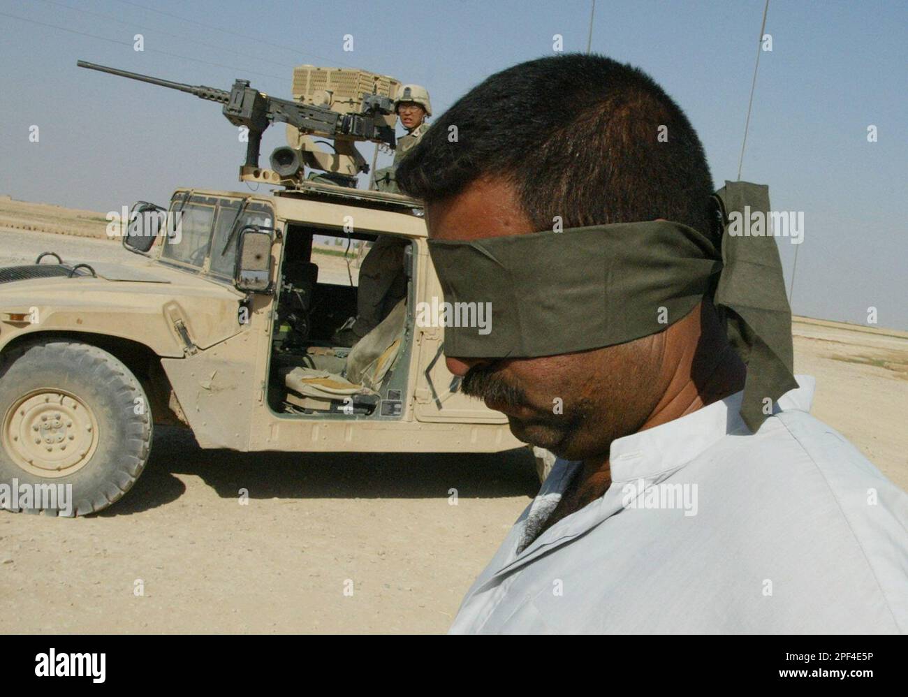 A suspected Saddam Fedayeen member waits next to a Humvee from the U.S ...