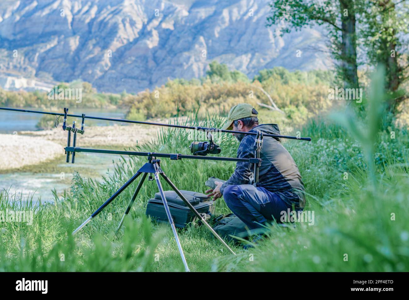Male angler preparing on the river for a day of carpfishing, setting up ...