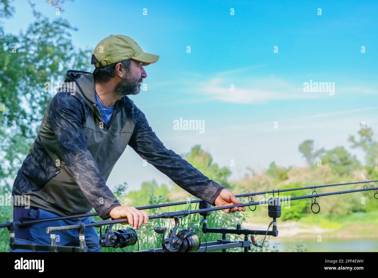 Adult male angler taking the rod from his stand for the bite of a fish ...