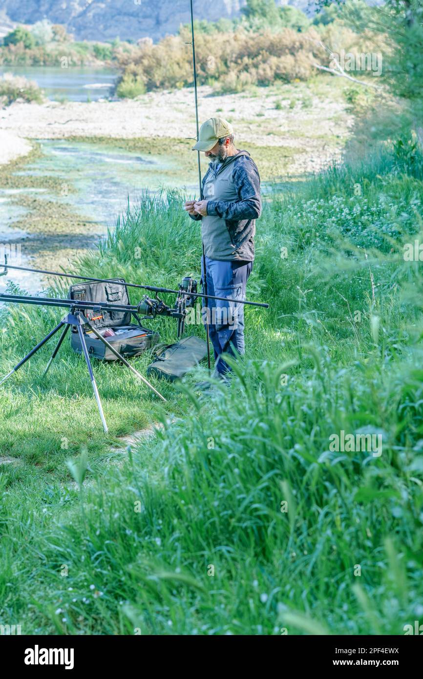 Male angler preparing on the river for a day of carpfishing, setting up ...