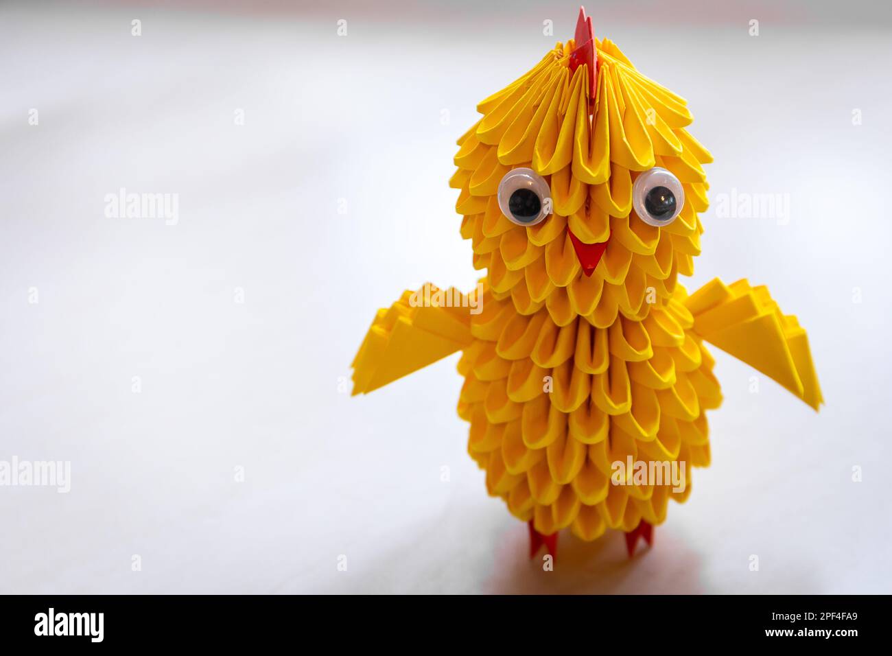 Handmade yellow origami Easter chick against white background, copy ...