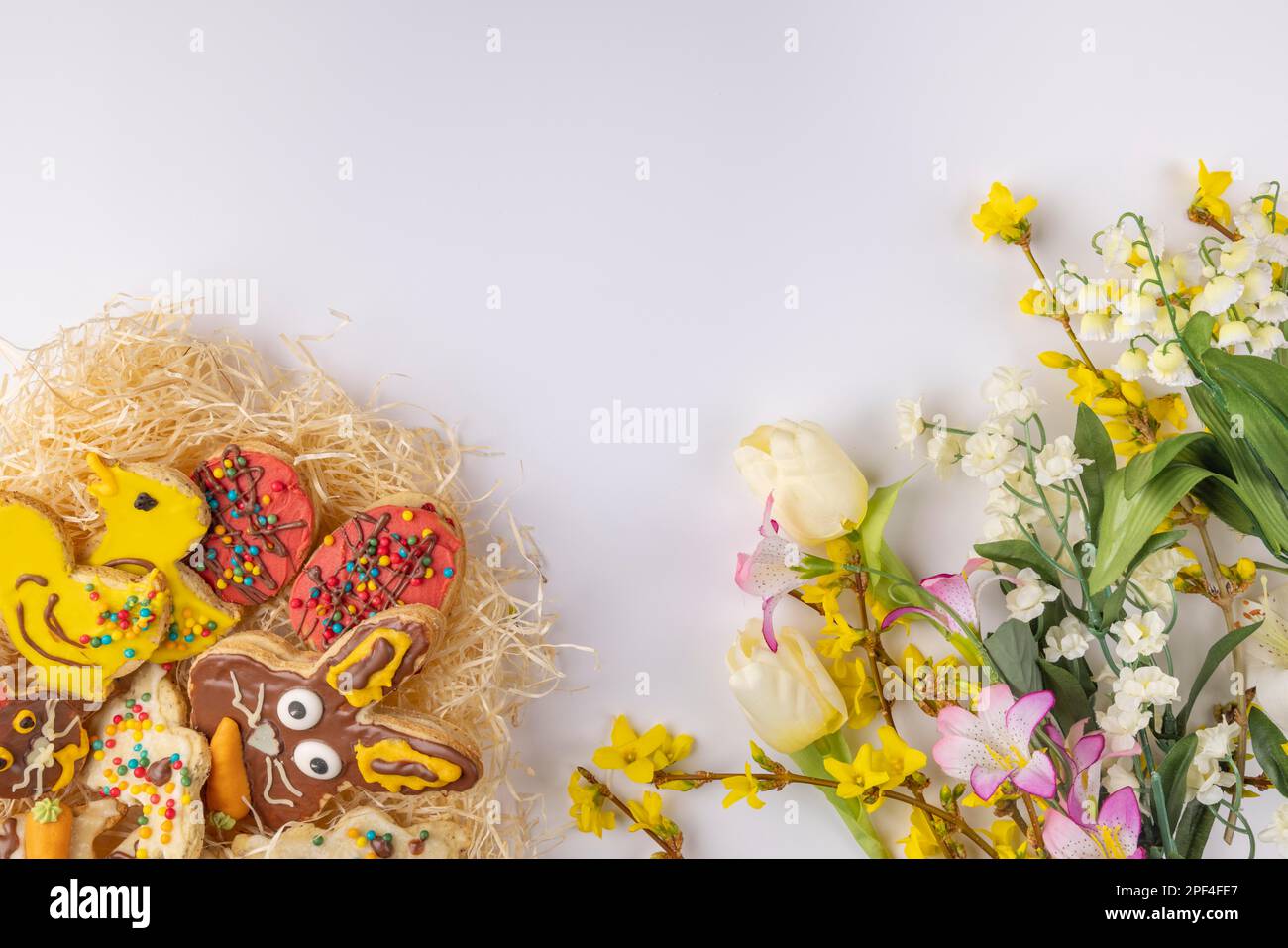 Colourful decorated Easter biscuits in nest, spring flowers, white ...