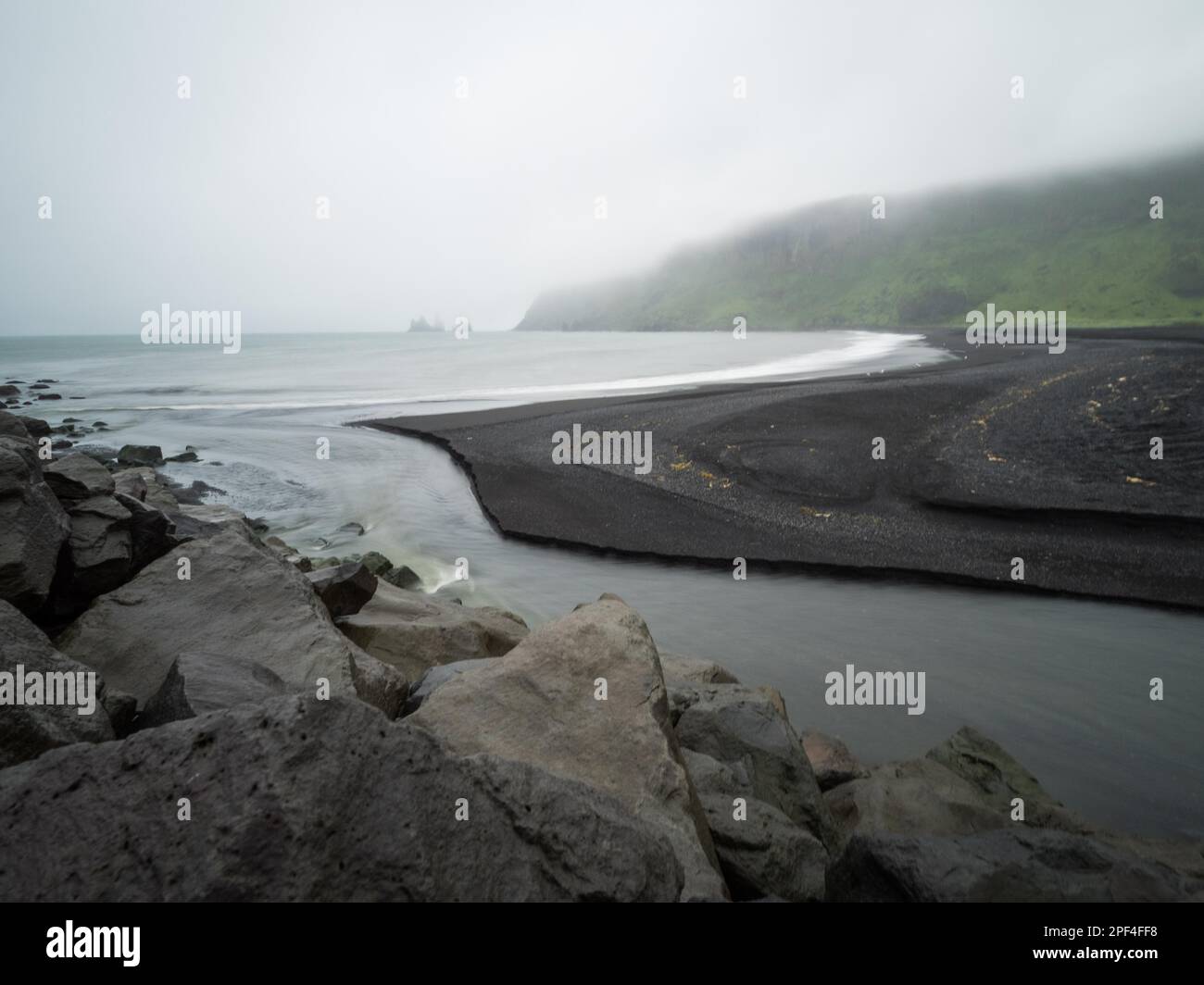 Rainy atmosphere, cliff in the fog, rock Reynisdrangar in the water, at ...