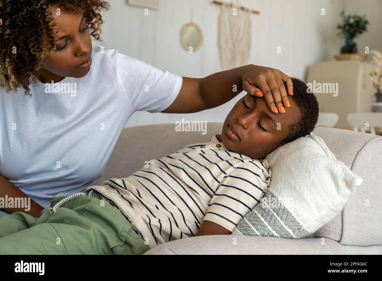 Loving worried African American woman mother taking care of sick child son at home Stock Photo ...