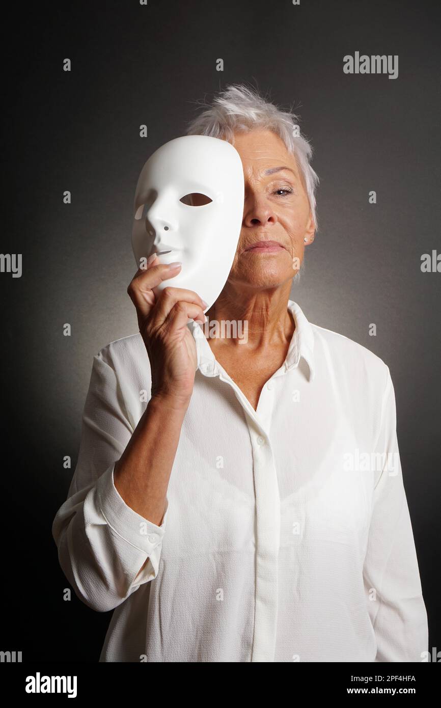 serious looking mature woman revealing true face behind mask Stock ...