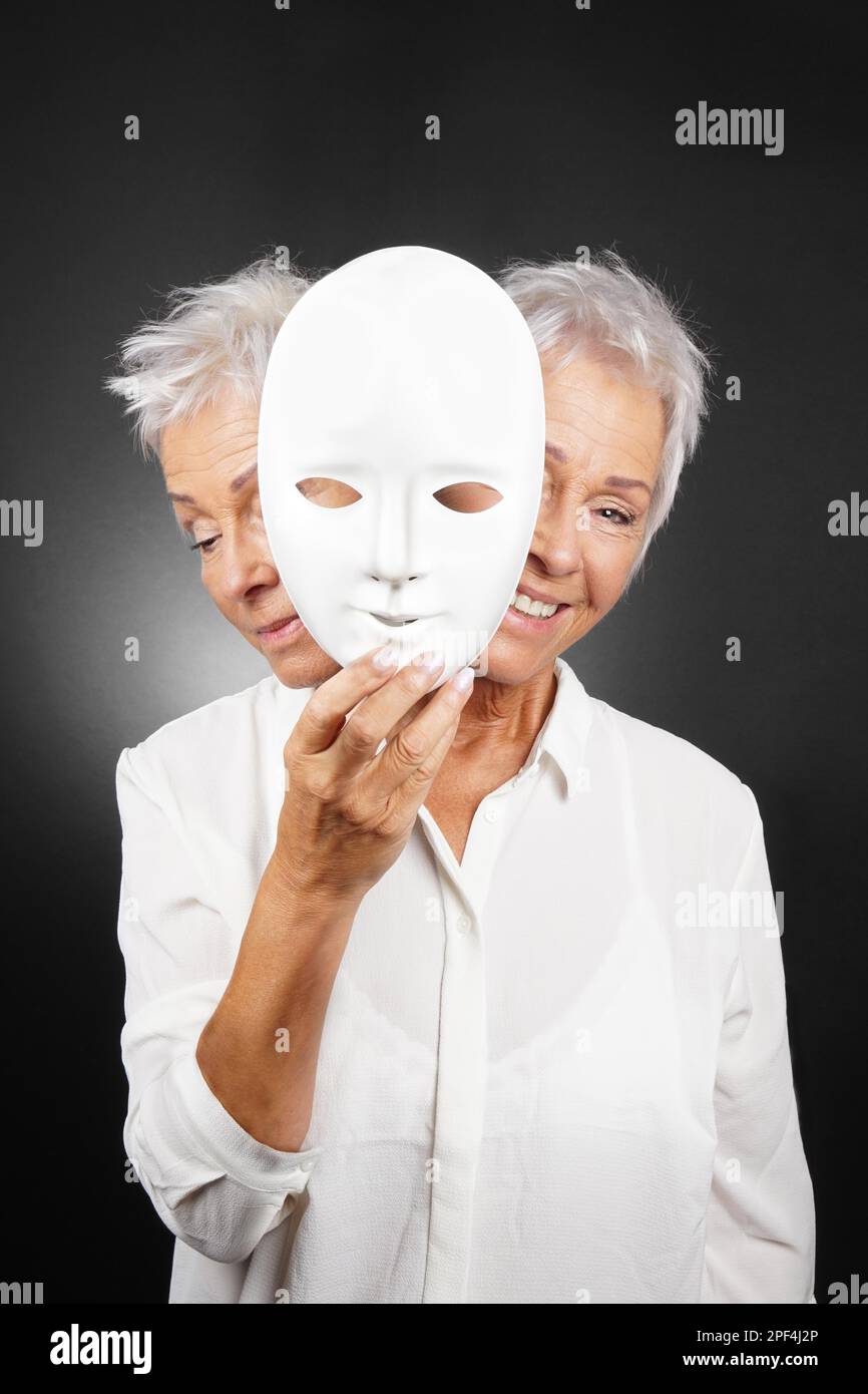 older woman hiding happy and sad face behind mask, concept for manic ...