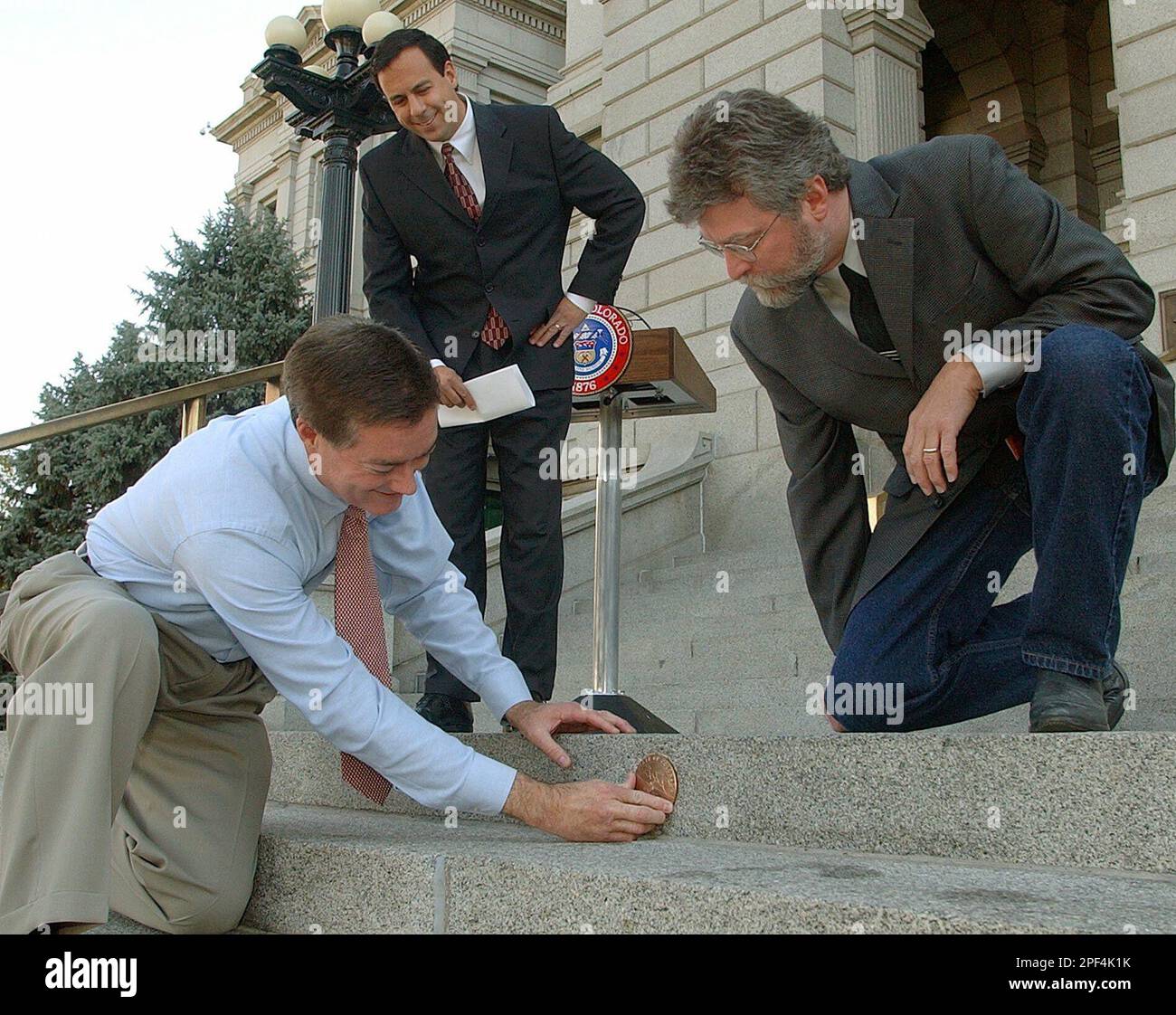 Colorado Gov. Bill Owens, left, sets a new "Mile High" marker in place ...