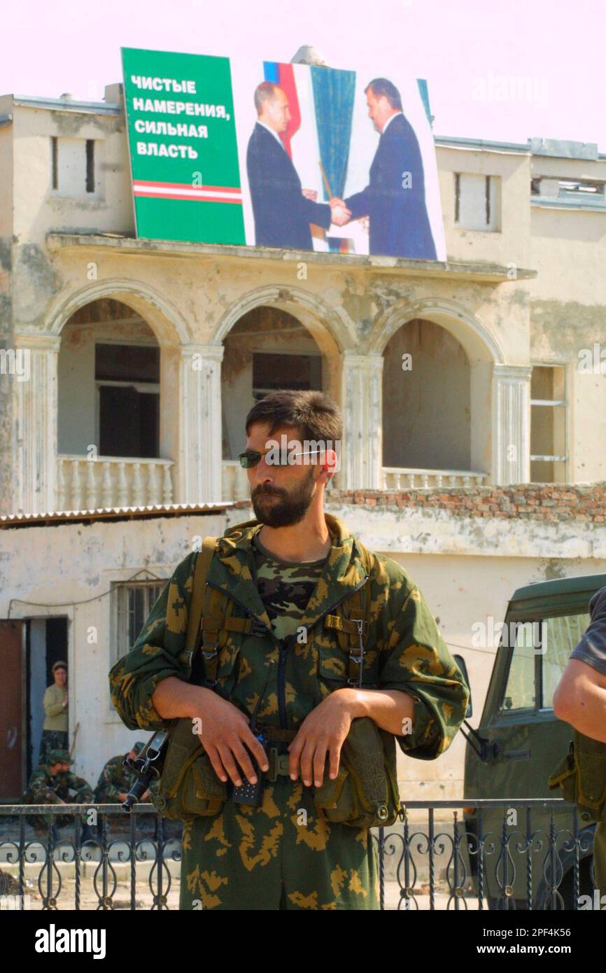 A Chechen police officer stands at a pre-election poster, which depicts ...