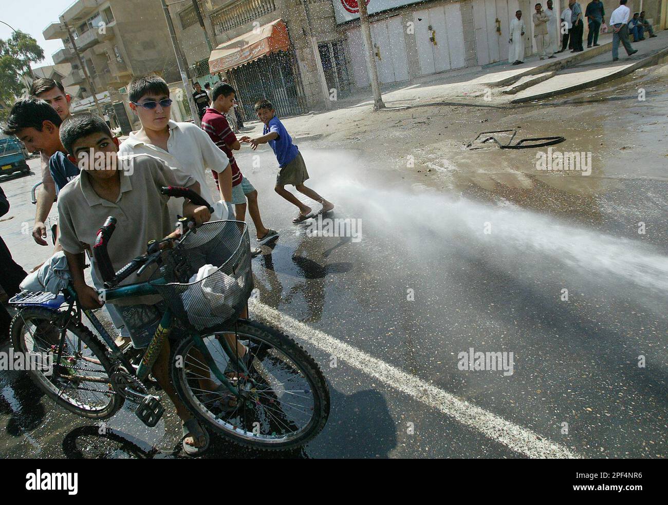 Iraqi firefighters use a firehose to chase away Iraqi children ...