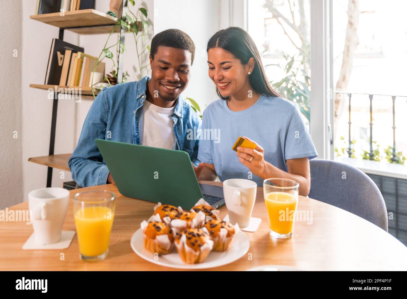 Couple making purchase online with the computer while having breakfast ...