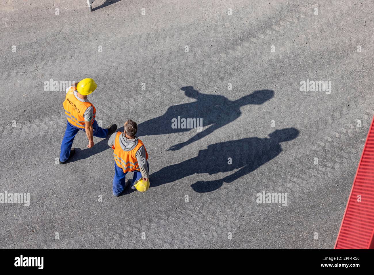 Construction workers with hard hats walking on a street, casting a ...