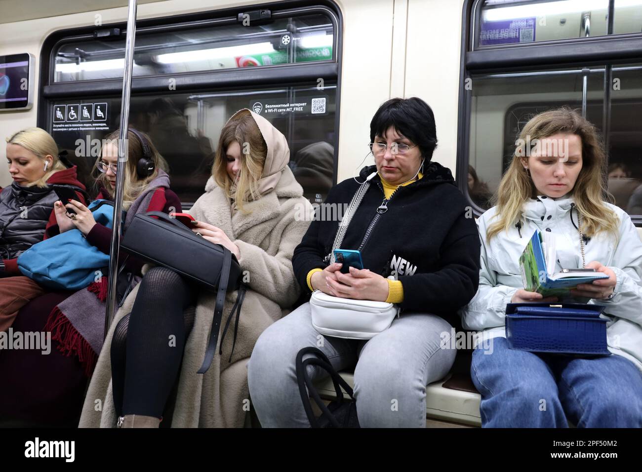 People in a metro train, women passengers seating with smartphones ...