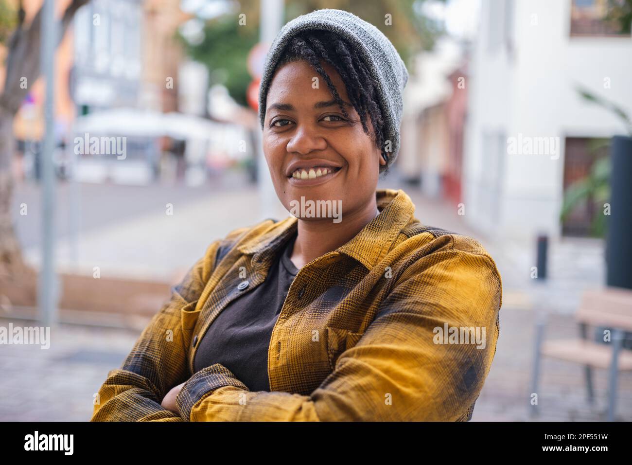 Woman with dreadlocks hairstyle and urban type hat with crossed arms ...
