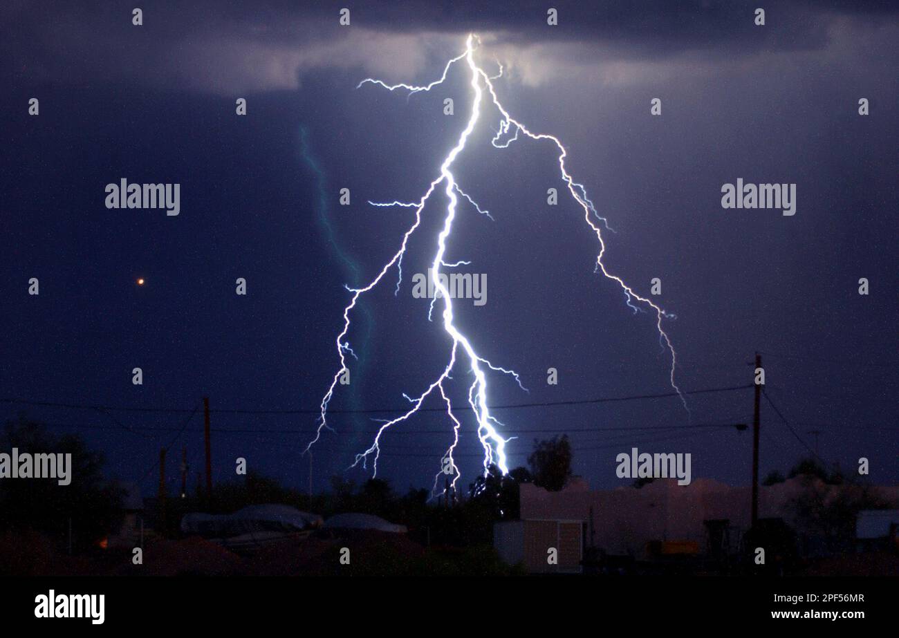 The Planet Mars Left Rises In The Night Sky During A Lightning Storm