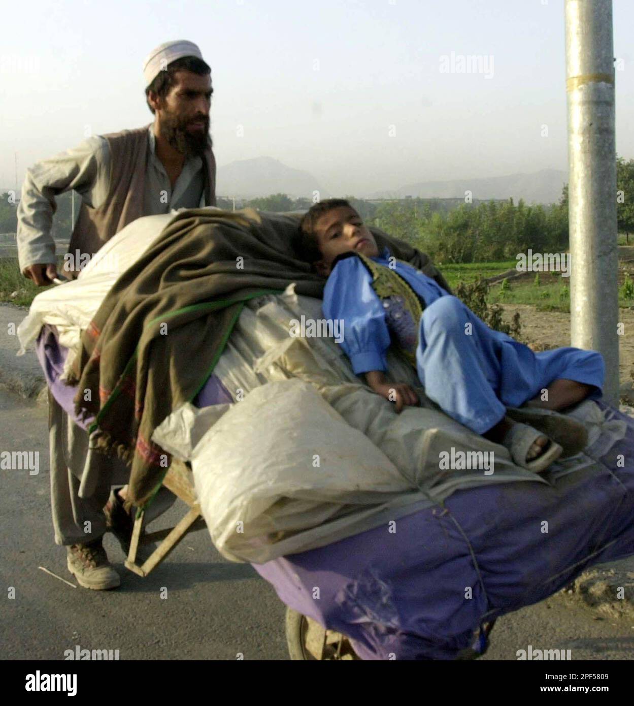 An Afghan shopkeeper Abdullah Khan pushes handcart carrying his ...