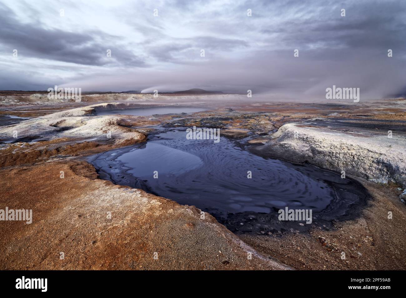 Wide view over a volcanic landscape in reddish and yellowish tones, mud ...