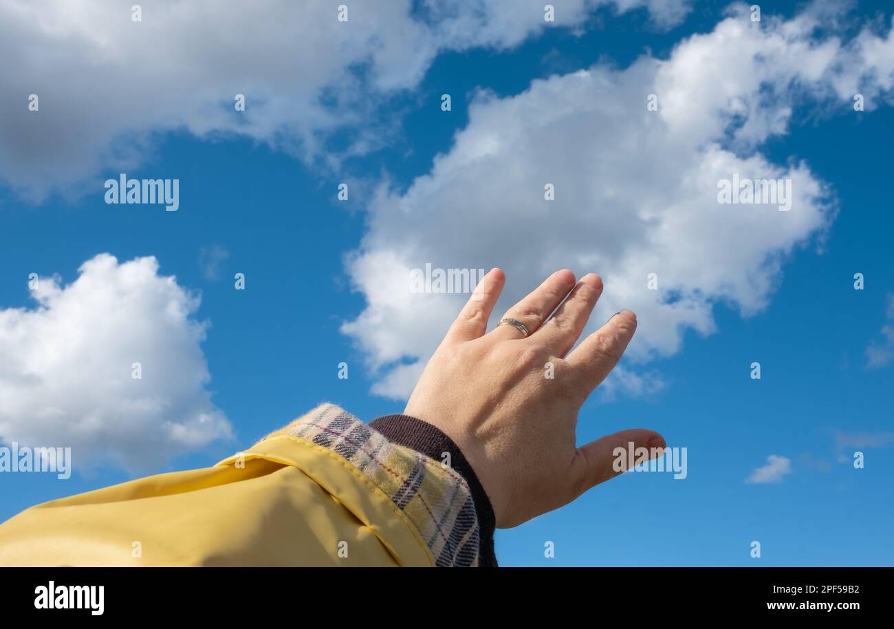 Adult hand reaching out towards the sky. Hand touch the blue sky with ...