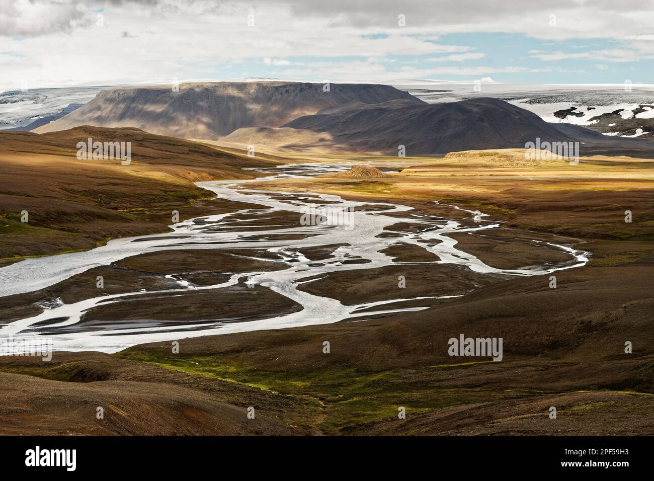 Wide view over a flat valley in the highlands of Iceland, a river winds ...