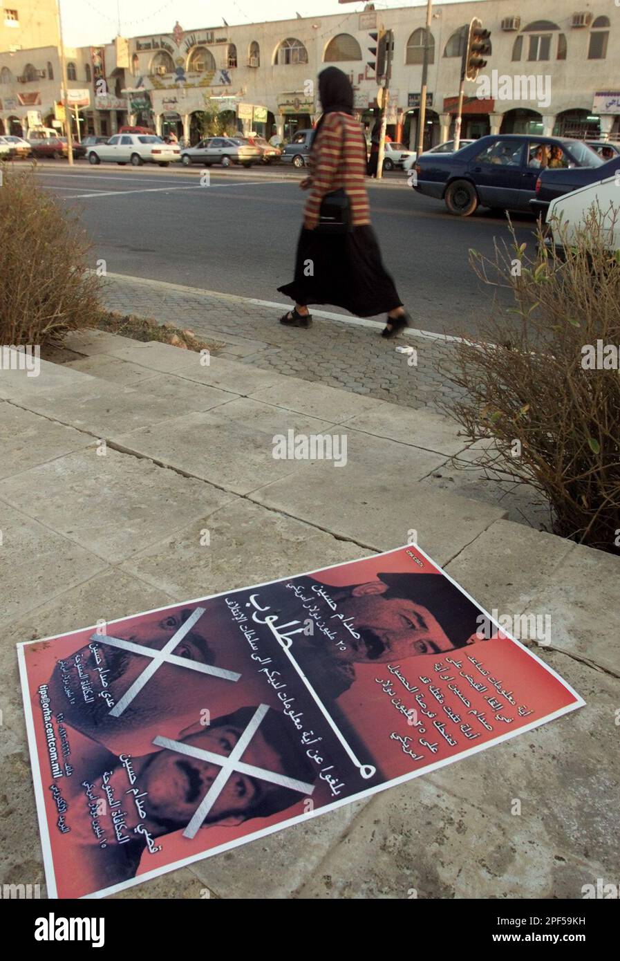 An Iraqi woman passes a new Saddam Hussein "Wanted for $25 millon ...