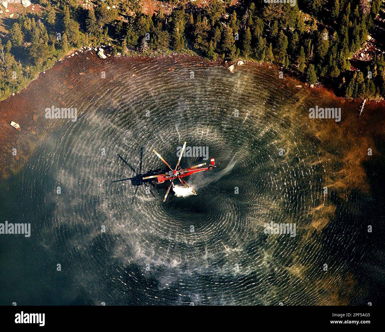 An aerial view shows a Sikorsky Skycrane helicopter drawing water from ...